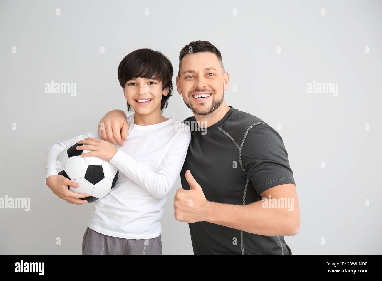 Father and little son with soccer ball on grey background Stock Photo ...