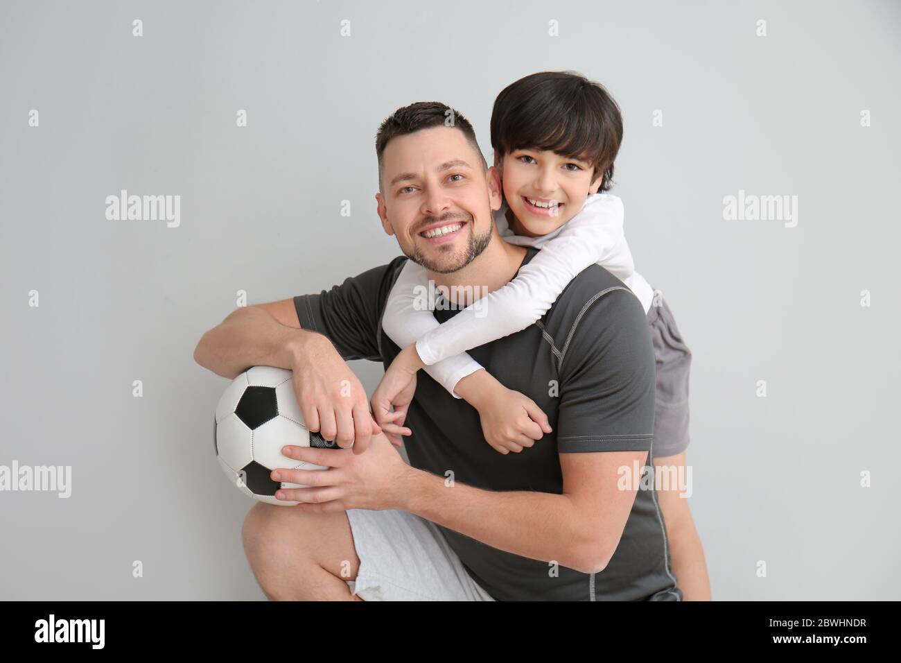 Father and little son with soccer ball on grey background Stock Photo ...