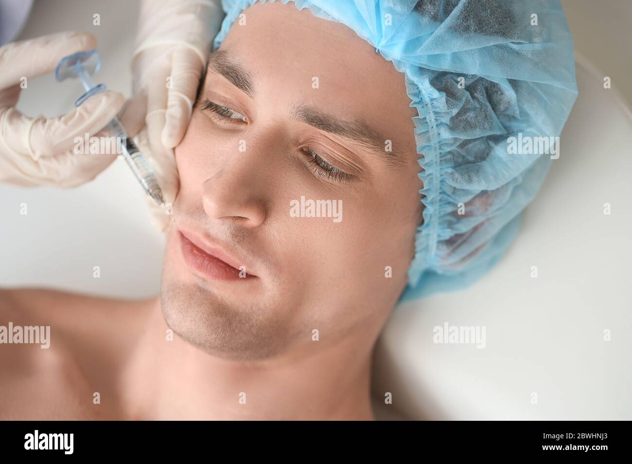 Handsome man receiving filler injection in beauty salon Stock Photo - Alamy