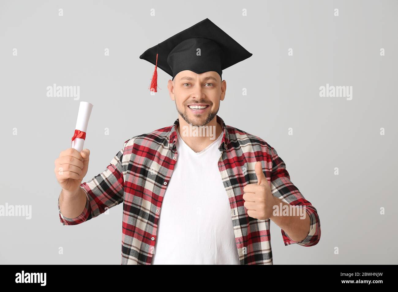 Man in graduation hat and with diploma on grey background Stock Photo ...