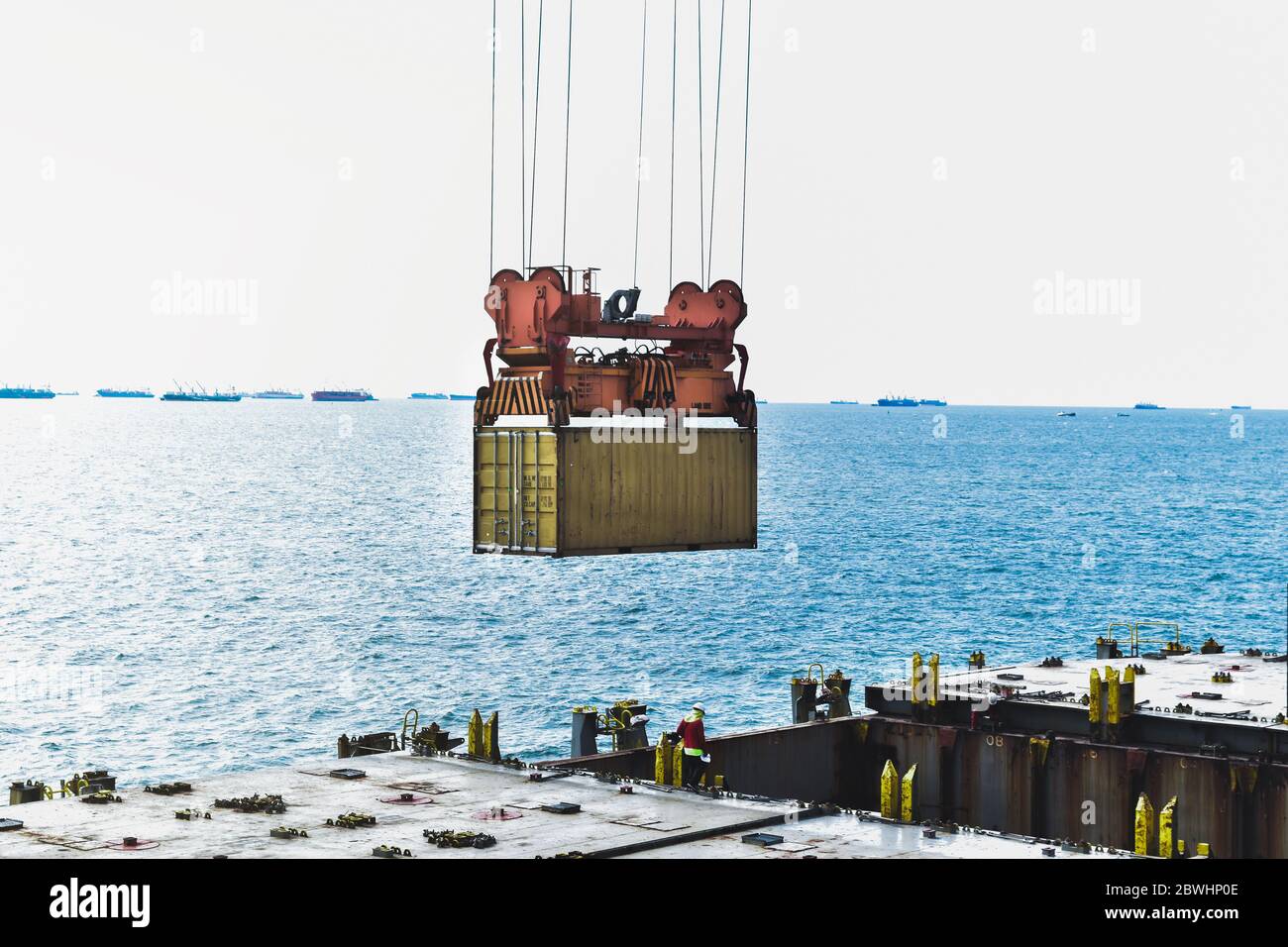 container box lifted up by spreader hang in the sky with sea background ...