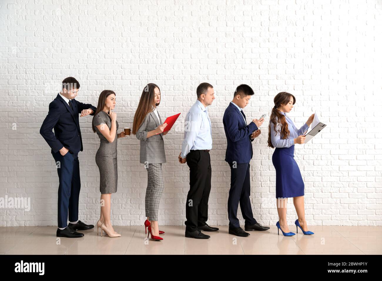 Business people waiting in line indoors Stock Photo - Alamy