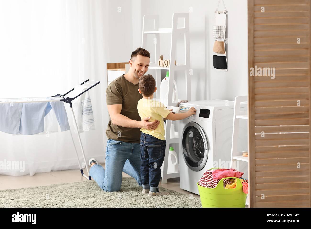 Man and his little son doing laundry at home Stock Photo - Alamy