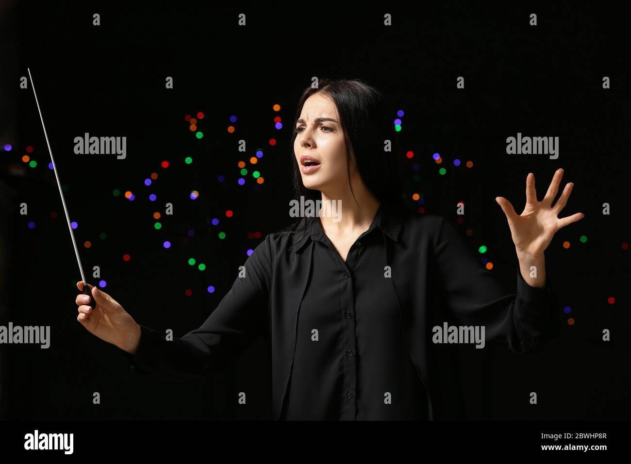 Young female conductor on dark background Stock Photo - Alamy