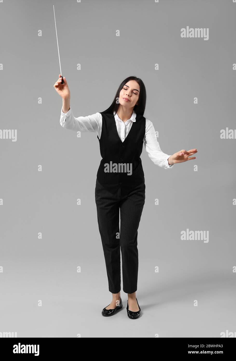 Young female conductor on grey background Stock Photo - Alamy