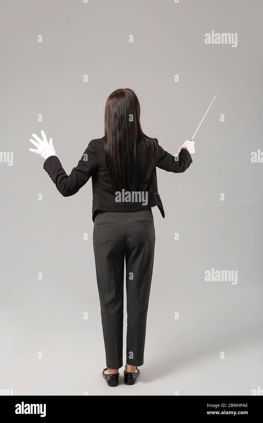 Young female conductor on grey background Stock Photo - Alamy