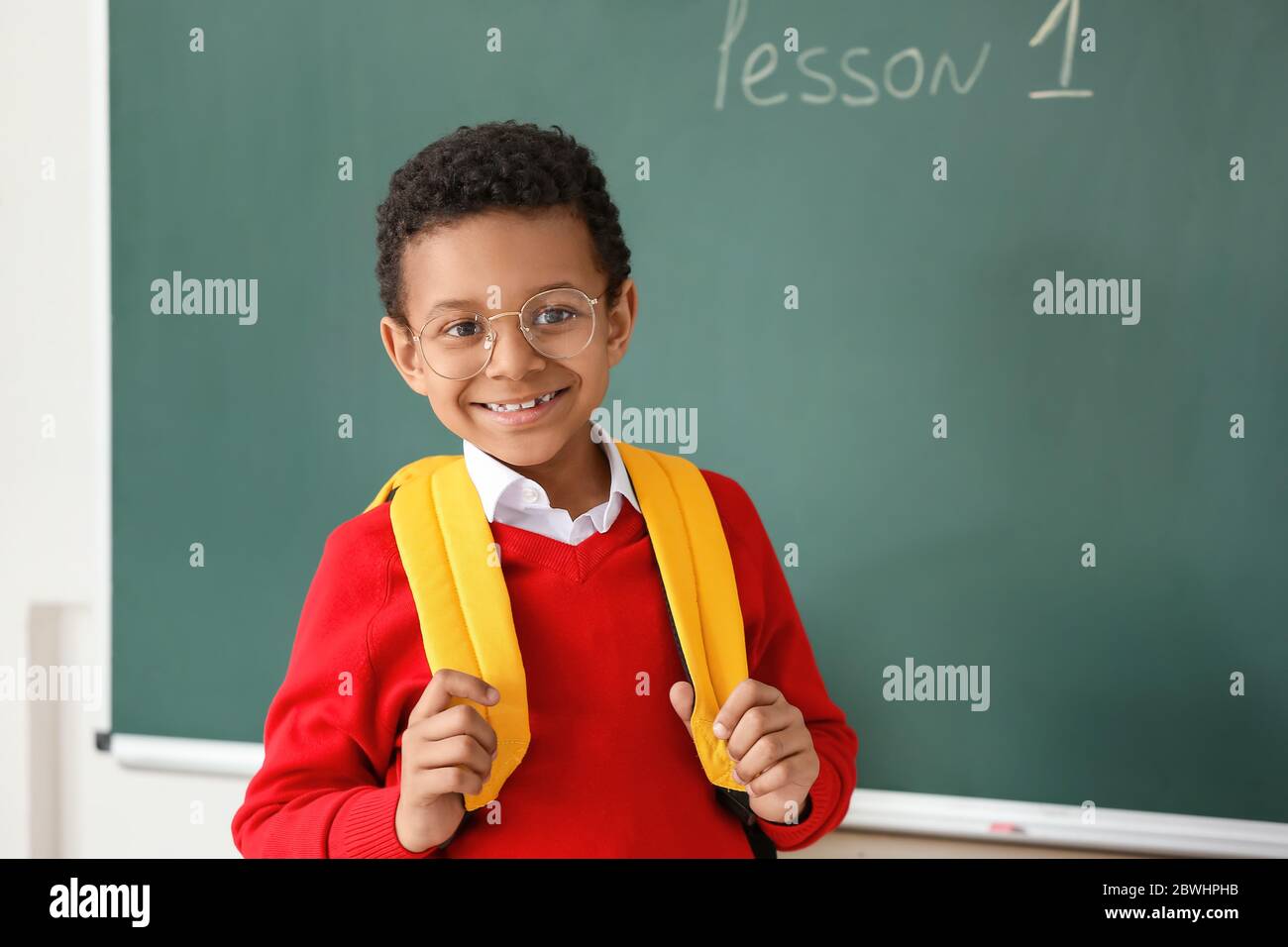 Cute little pupil near blackboard in classroom Stock Photo - Alamy