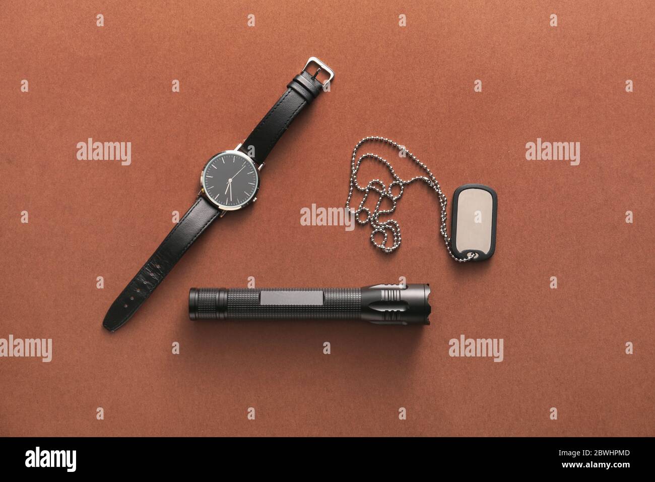 Modern flashlight with tag and watch on color background Stock Photo ...