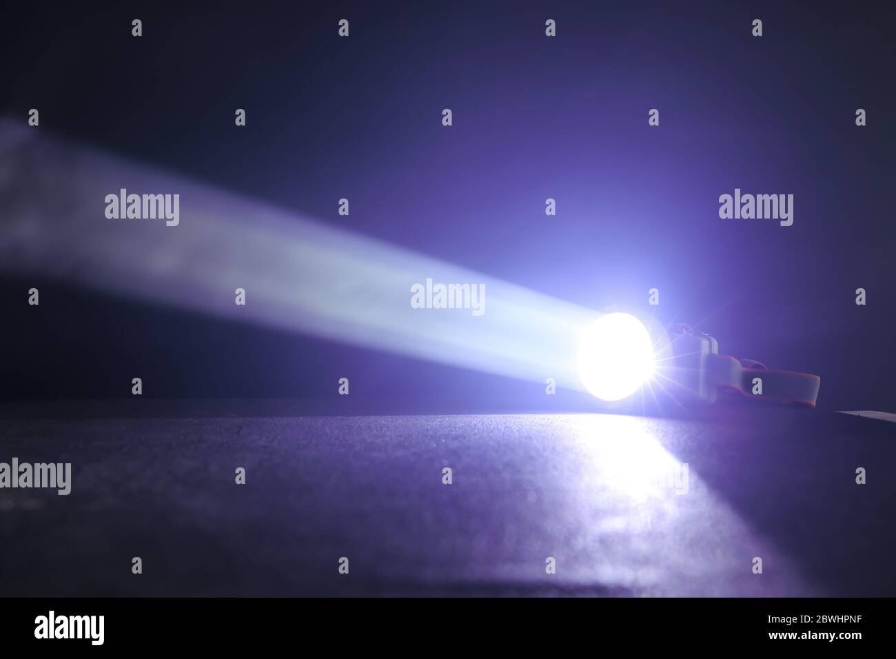 Glowing modern flashlight on dark background Stock Photo - Alamy