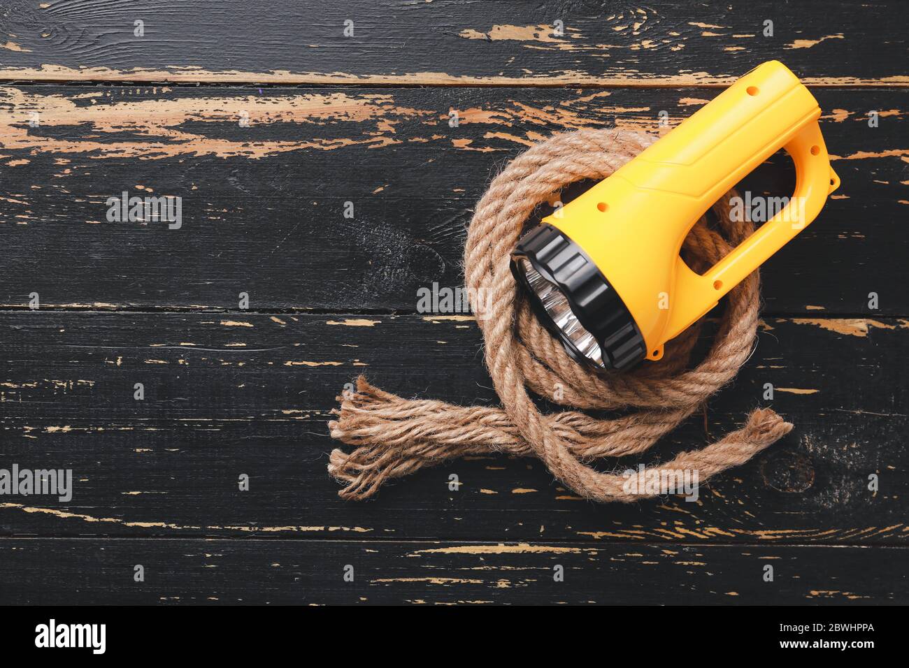 Modern flashlight with rope on dark wooden background Stock Photo - Alamy