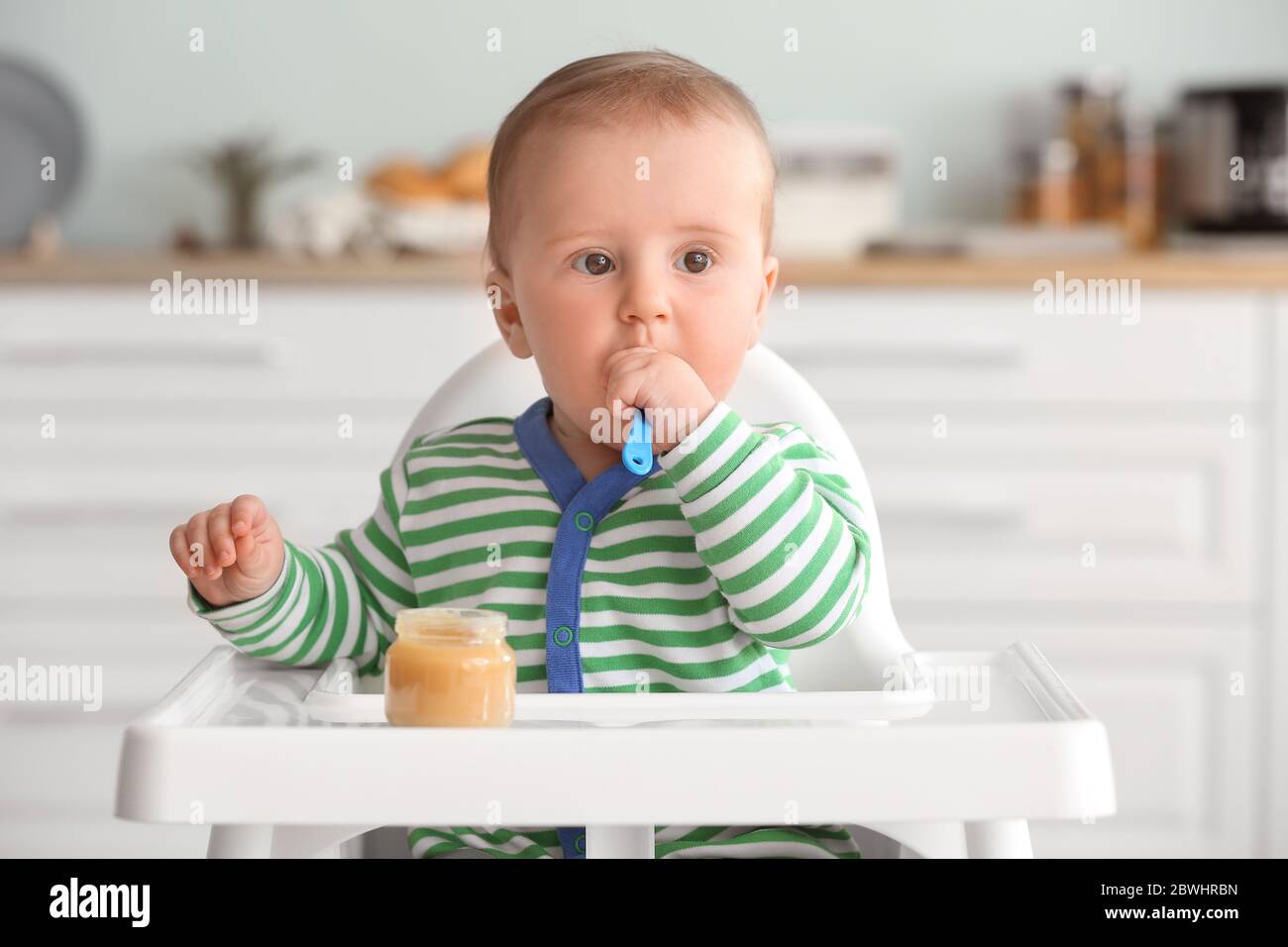 Cute little baby eating in kitchen Stock Photo - Alamy