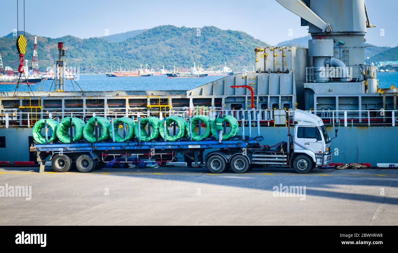 Truck load steel bundle alongside big ship. Steel cargo discharged from ...
