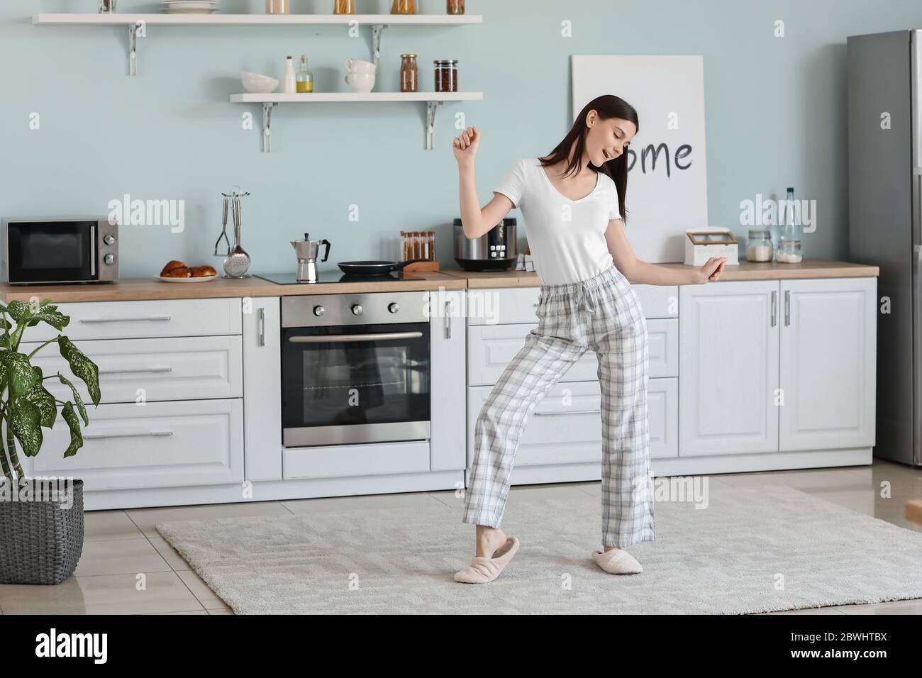 Beautiful young woman dancing in kitchen Stock Photo - Alamy