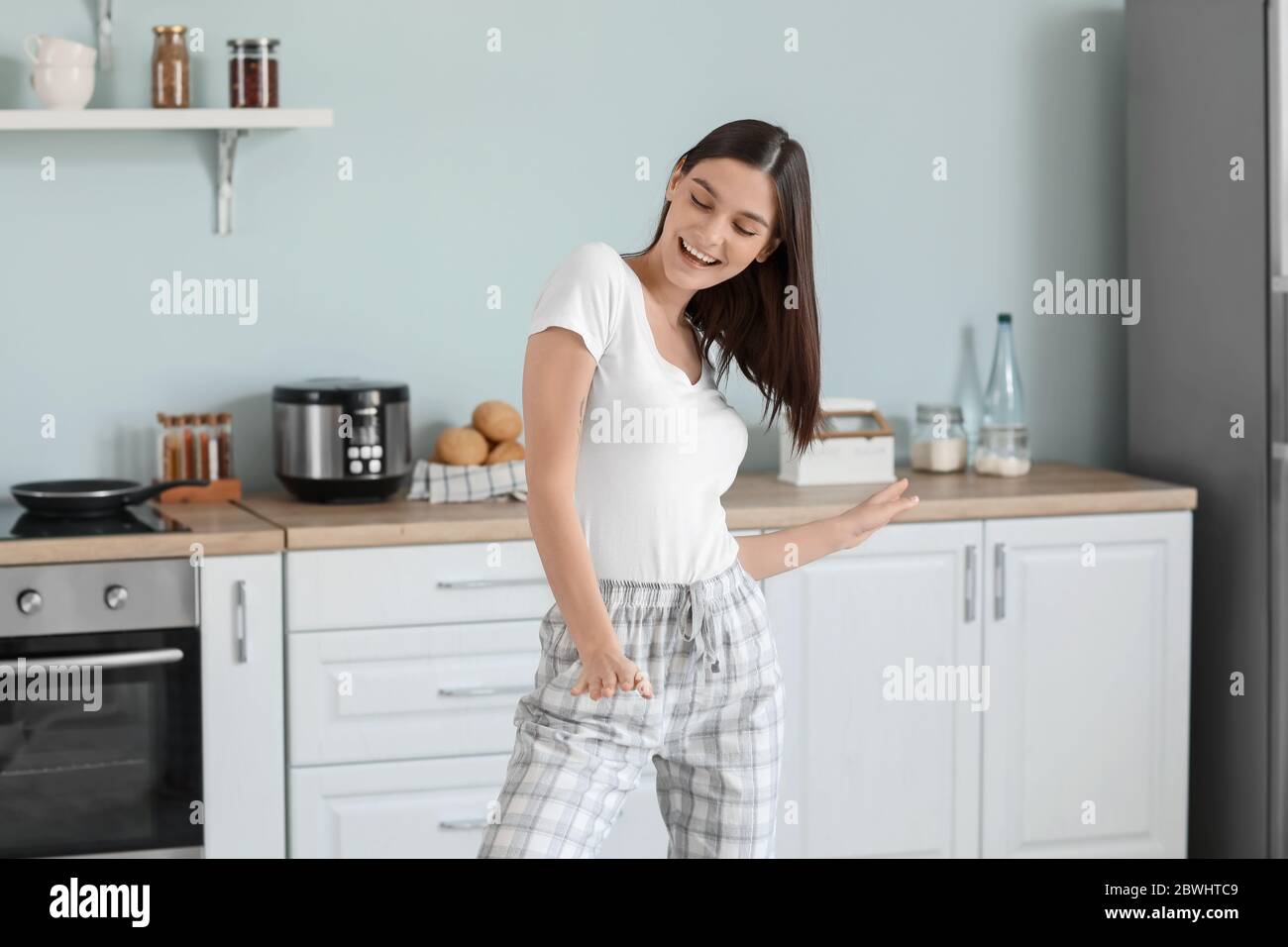 Beautiful young woman dancing in kitchen Stock Photo - Alamy