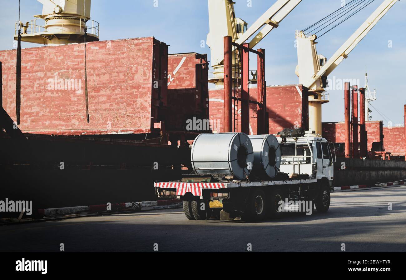 Truck load steel coils alongside big ship. Steel cargo discharged from ...