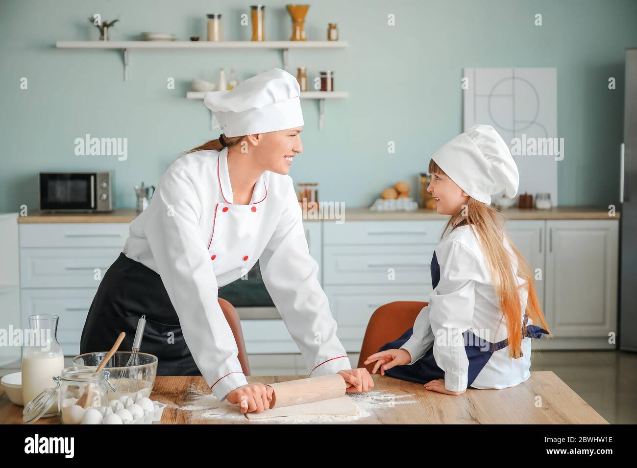 Female chef and her little daughter cooking in kitchen Stock Photo - Alamy
