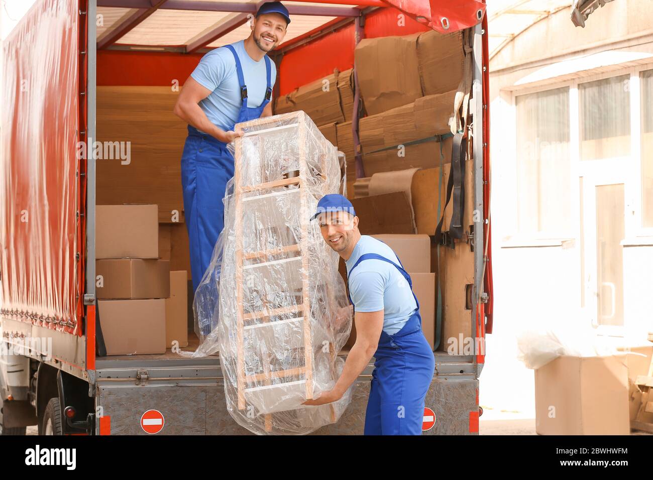 Loaders taking furniture from truck outdoors Stock Photo - Alamy