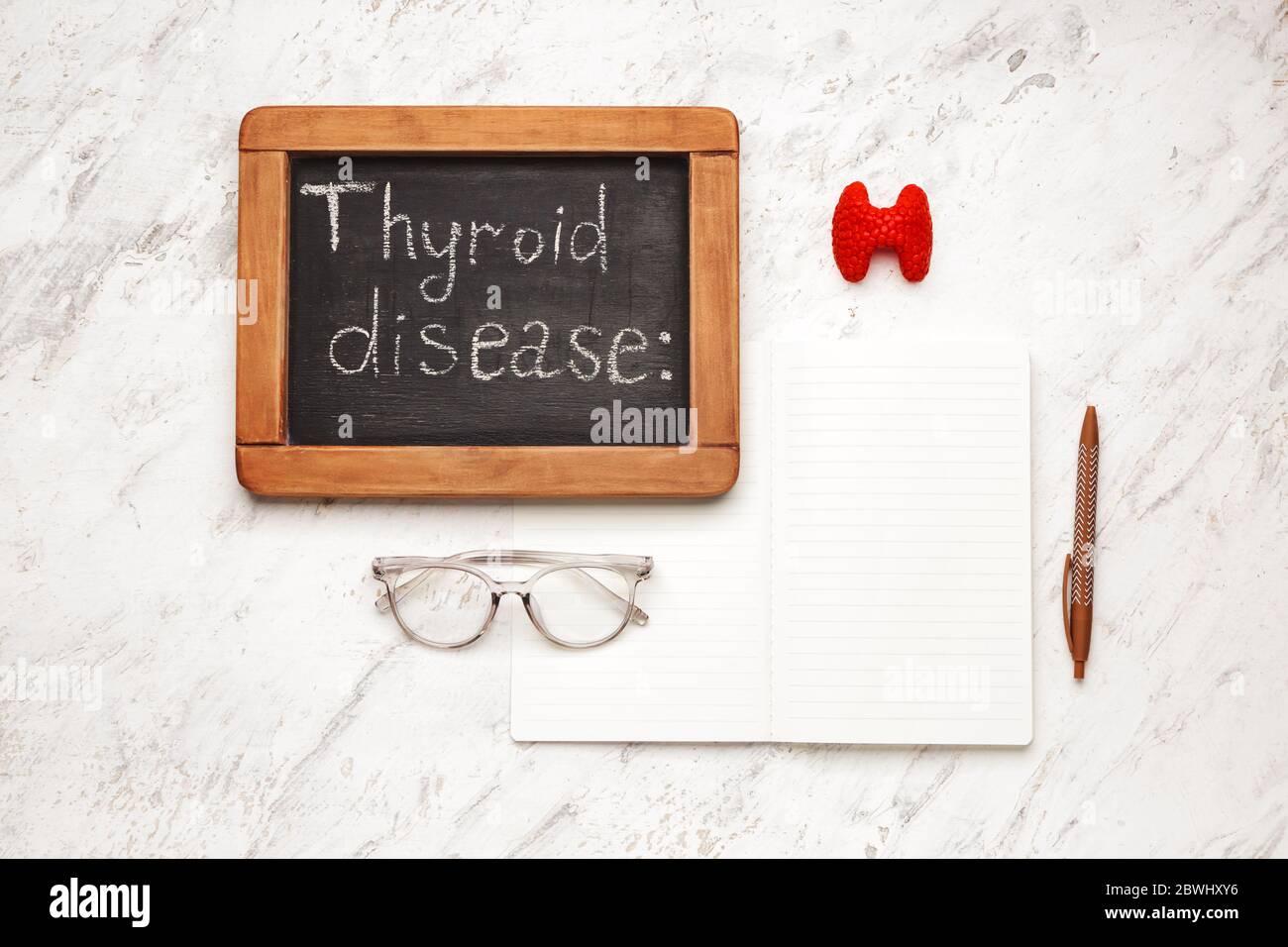 Chalkboard with text THYROID DISEASE and notebook on white background ...