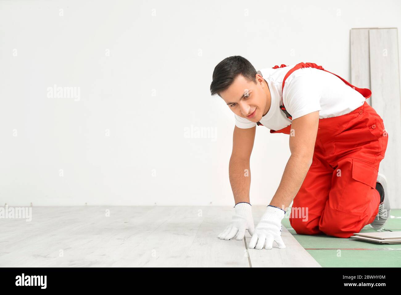 Carpenter installing laminate flooring in room Stock Photo - Alamy