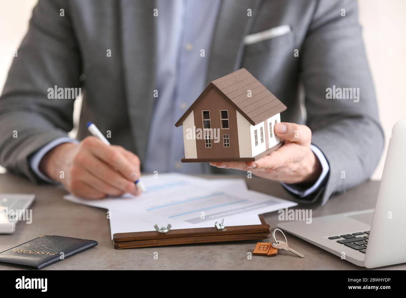 Male agent with home insurance form and model of house, closeup Stock ...