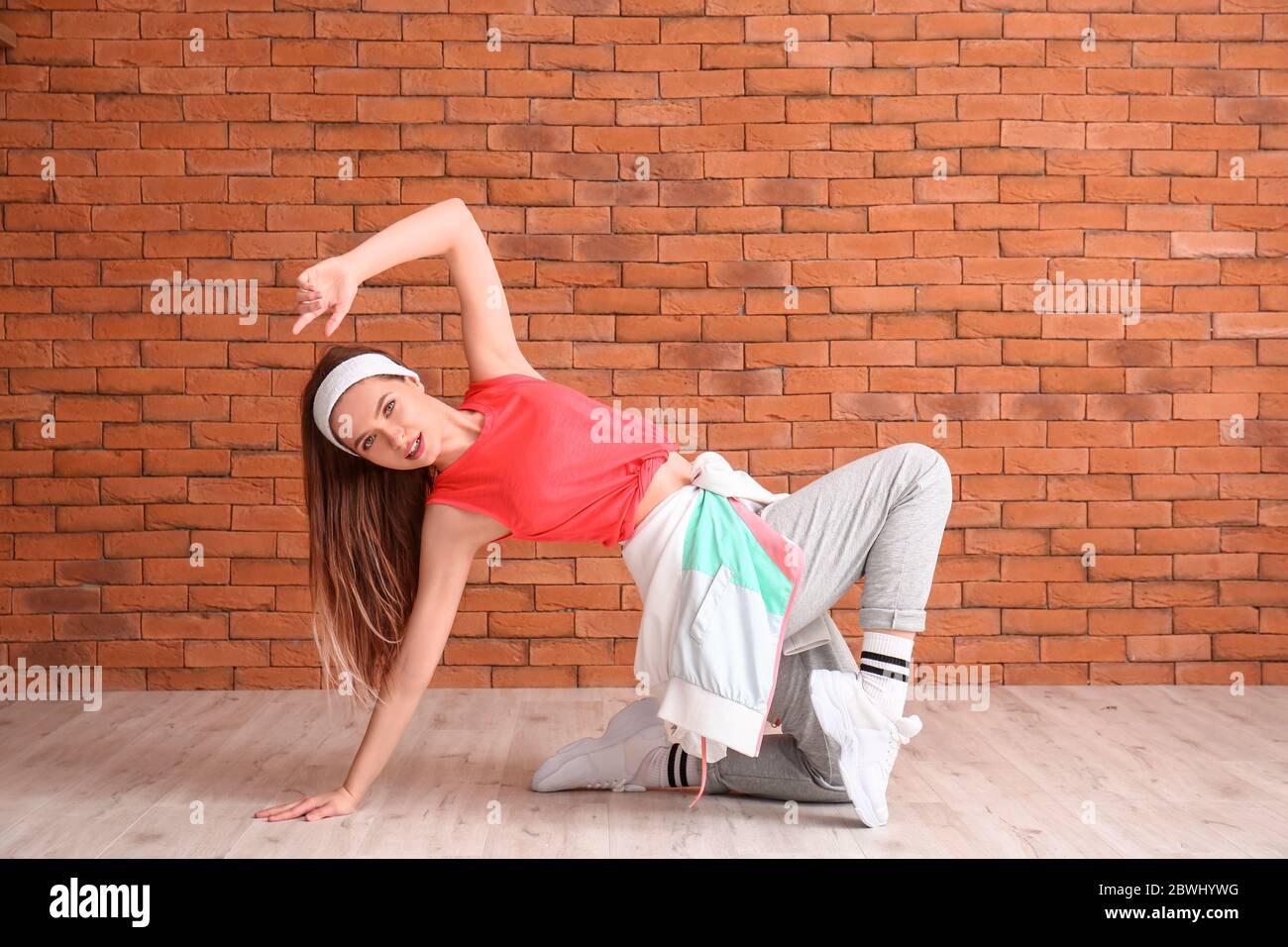 Young female hip-hop dancer against brick wall Stock Photo - Alamy