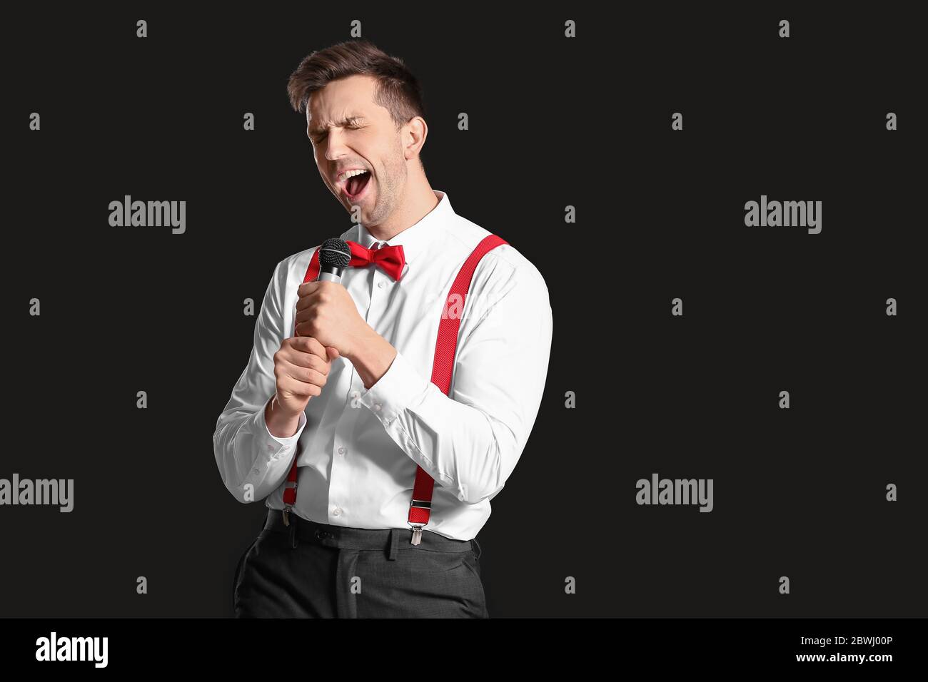 Young man singing on dark background Stock Photo - Alamy