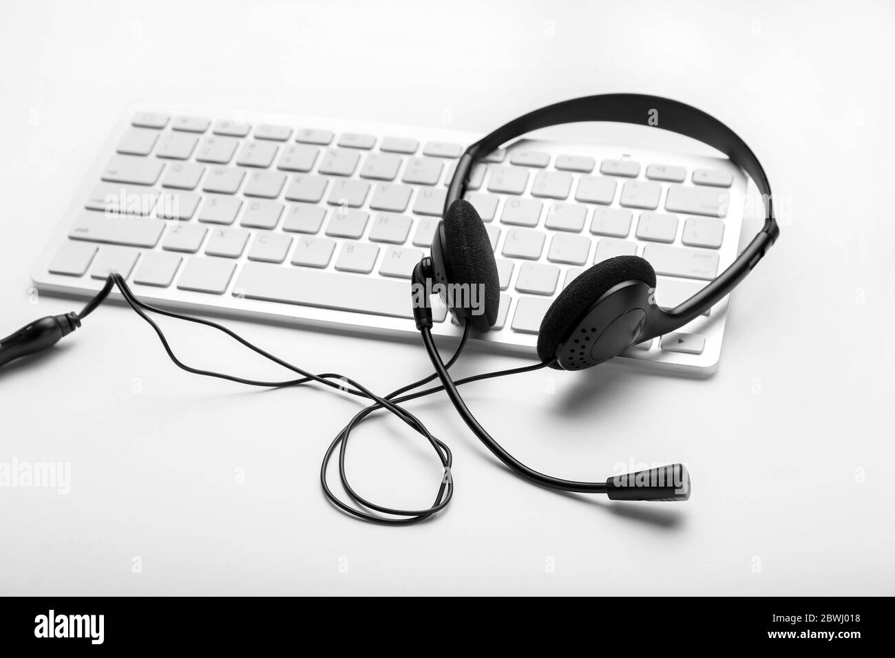 PC keyboard with headset on white background Stock Photo - Alamy
