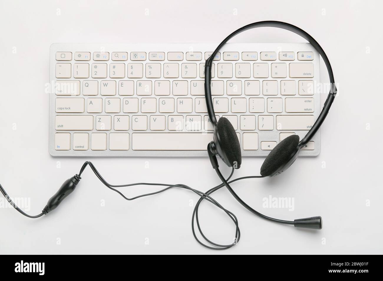 PC keyboard with headset on white background Stock Photo - Alamy