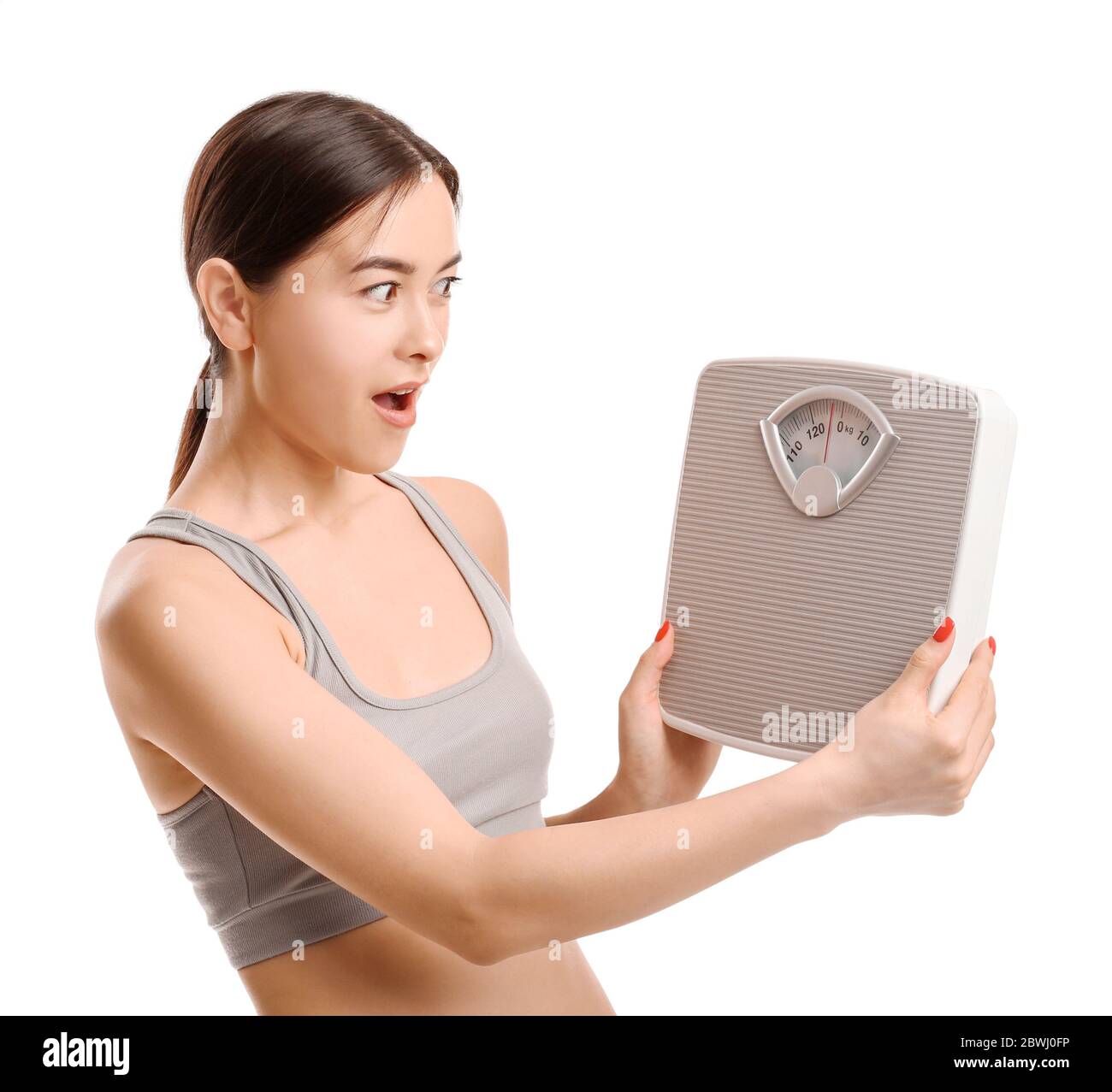 Shocked young woman with weight scales on white background Stock Photo ...