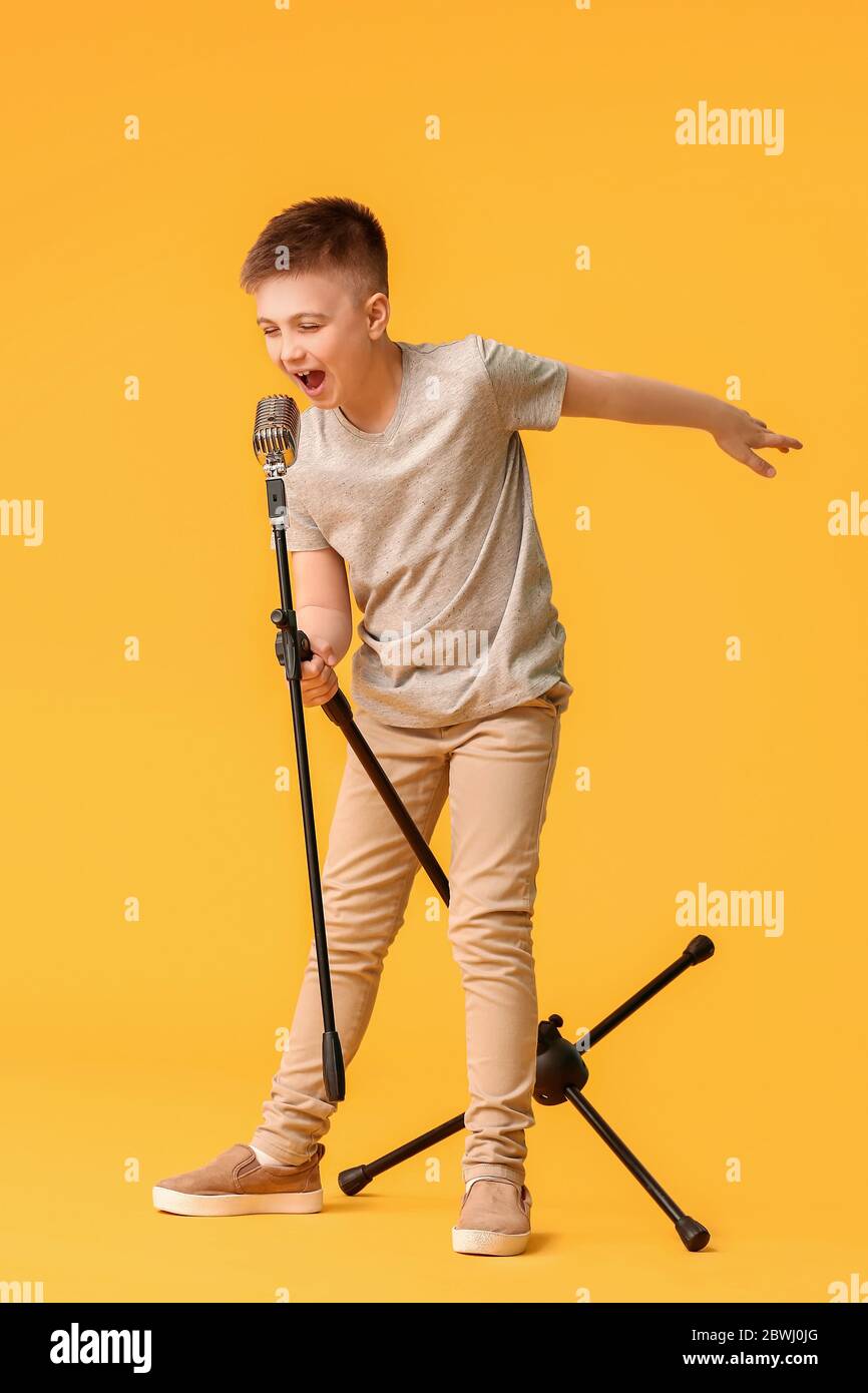 Cute little boy singing against color background Stock Photo - Alamy
