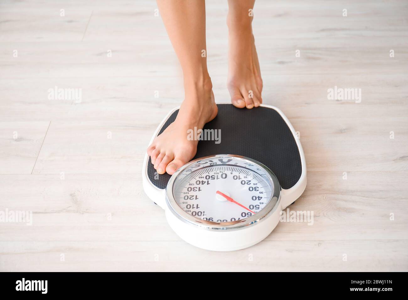 Young woman measuring her weight at home Stock Photo - Alamy