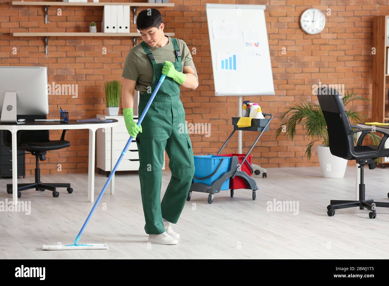 Male janitor mopping floor in office Stock Photo - Alamy