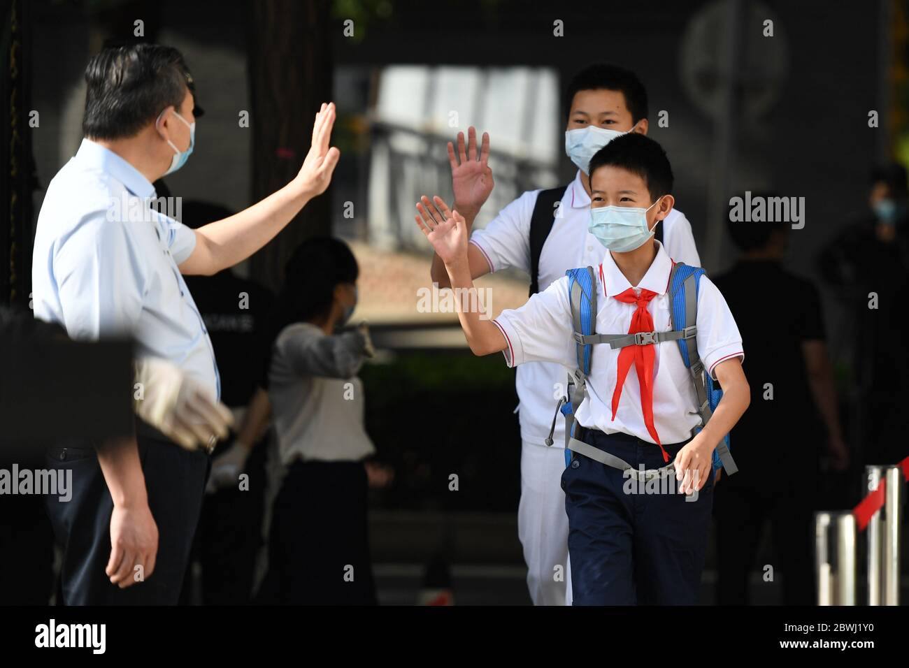 Beijing, China. 1st June, 2020. Students greet a teacher when entering ...