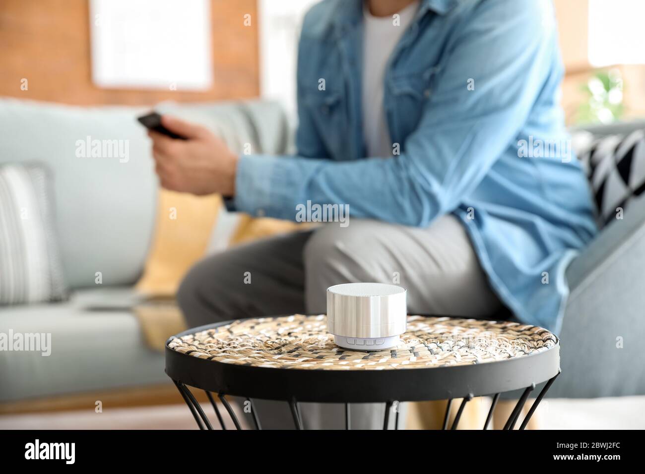Young man with smart home assistant device in room Stock Photo - Alamy