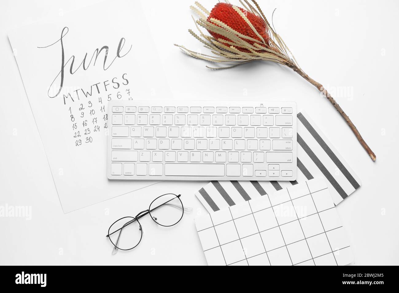 Computer keyboard with notebooks, eyeglasses and calendar on white ...