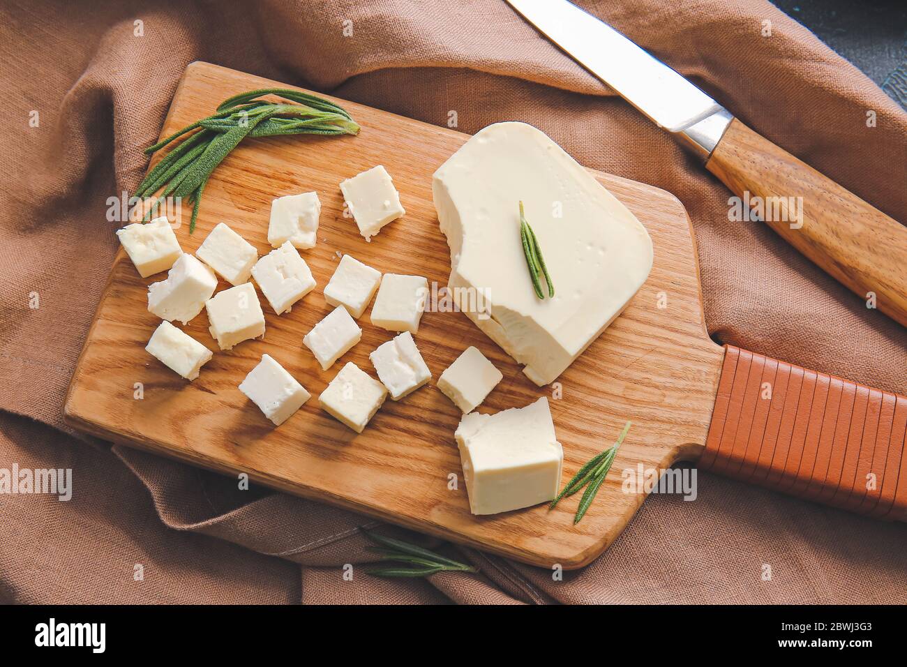 Board with tasty cut feta cheese on table Stock Photo - Alamy