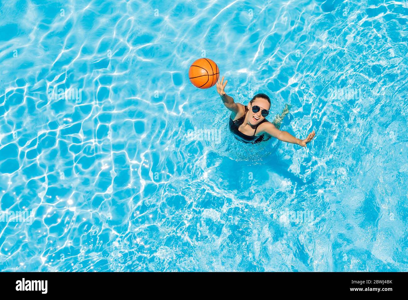 Young woman plays in the pool with a beach ball Stock Photo - Alamy