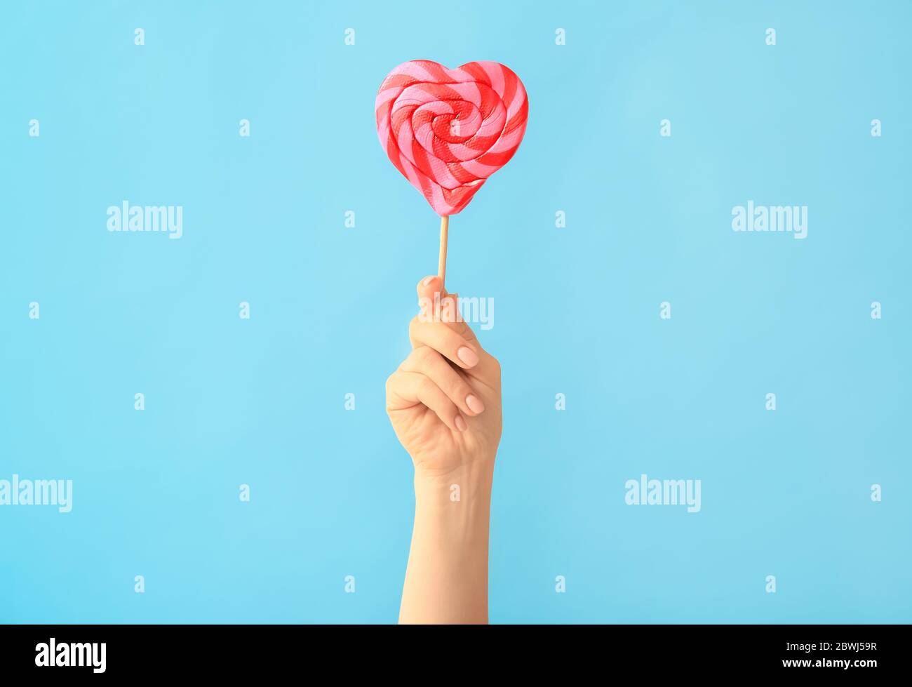 Hand with sweet lollipop on color background Stock Photo - Alamy