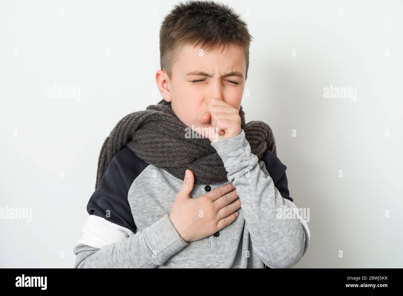 Ill coughing little boy on light background Stock Photo - Alamy