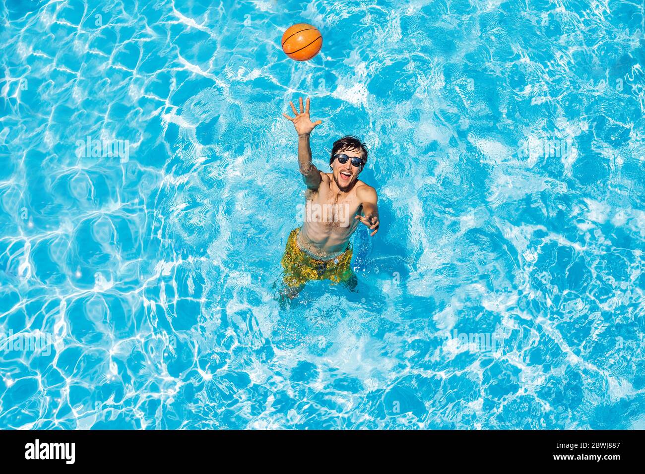 Man play in the pool with a beach ball Stock Photo - Alamy