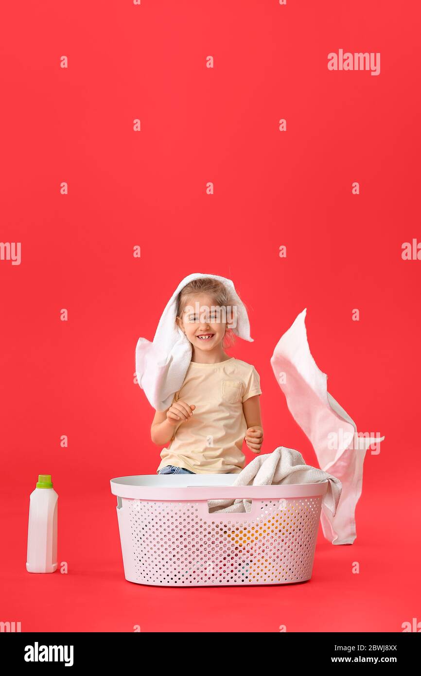 Happy little girl with laundry on color background Stock Photo - Alamy