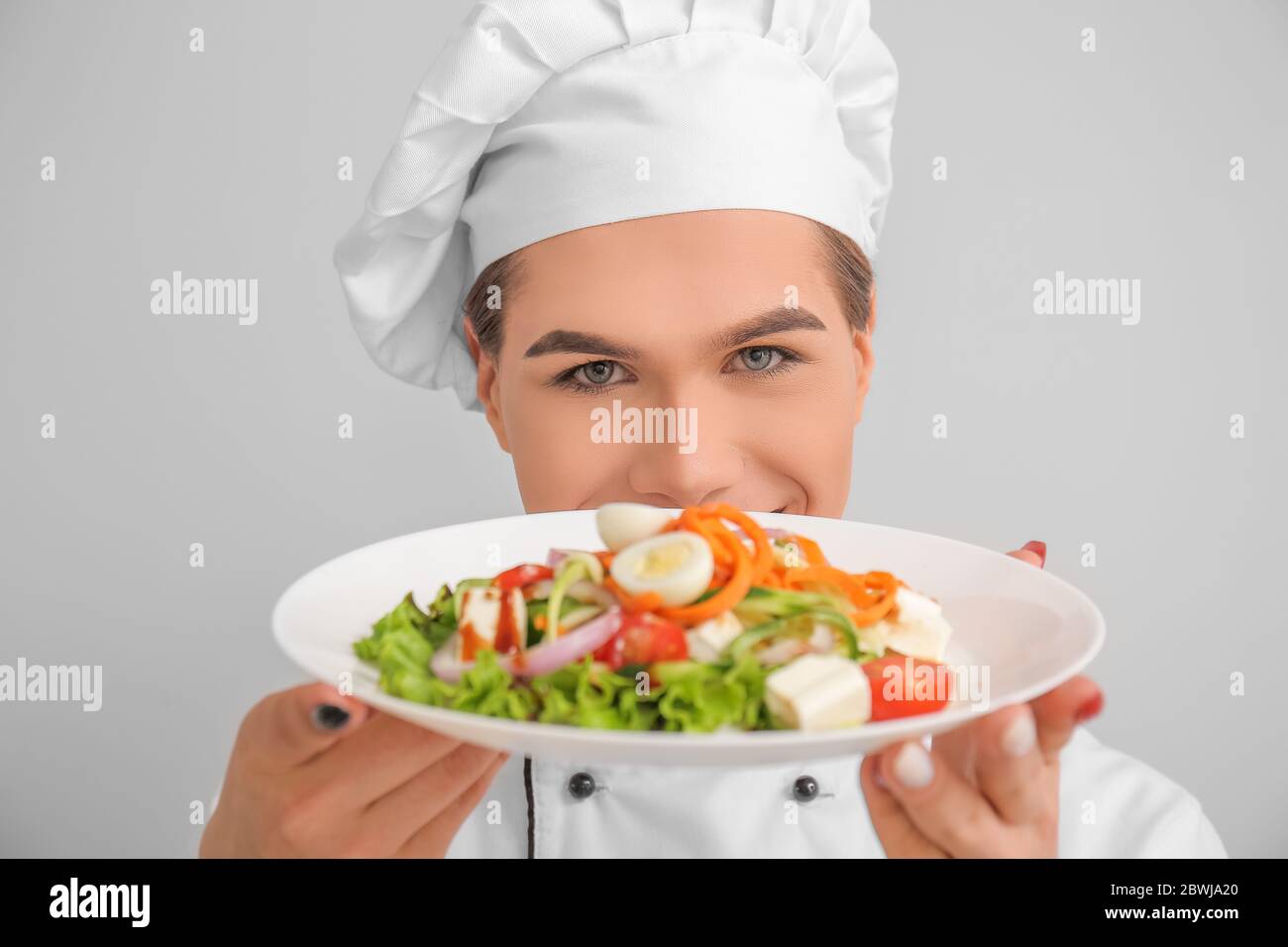 Transgender chef with salad on light background Stock Photo - Alamy