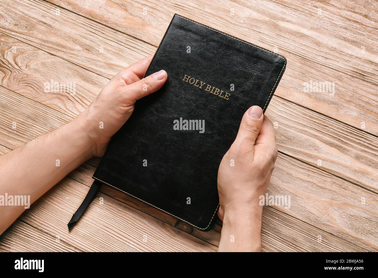 Hands of man with Bible on wooden background Stock Photo - Alamy