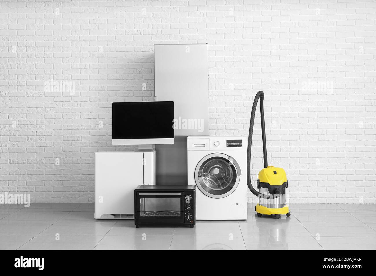 Different household appliances near white brick wall Stock Photo - Alamy