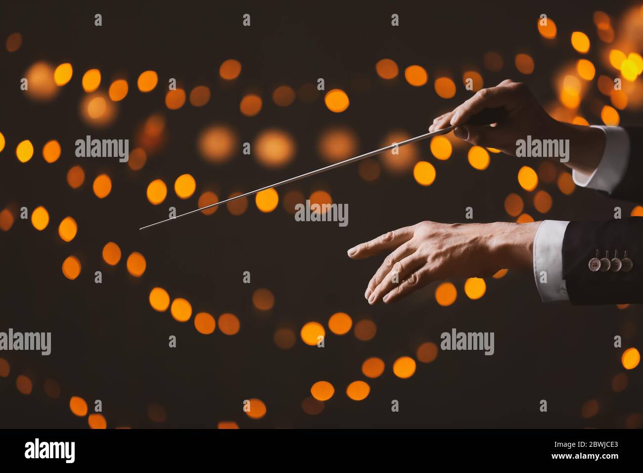 Hands of male conductor on dark background with defocused lights Stock ...