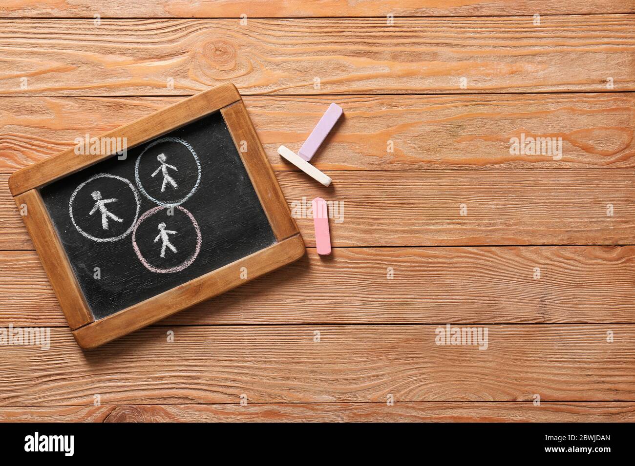 Chalkboard with drawn human figures on wooden background. Concept of ...