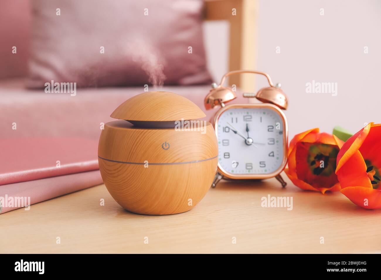 Aroma oil diffuser, clock and flowers on table in room Stock Photo - Alamy