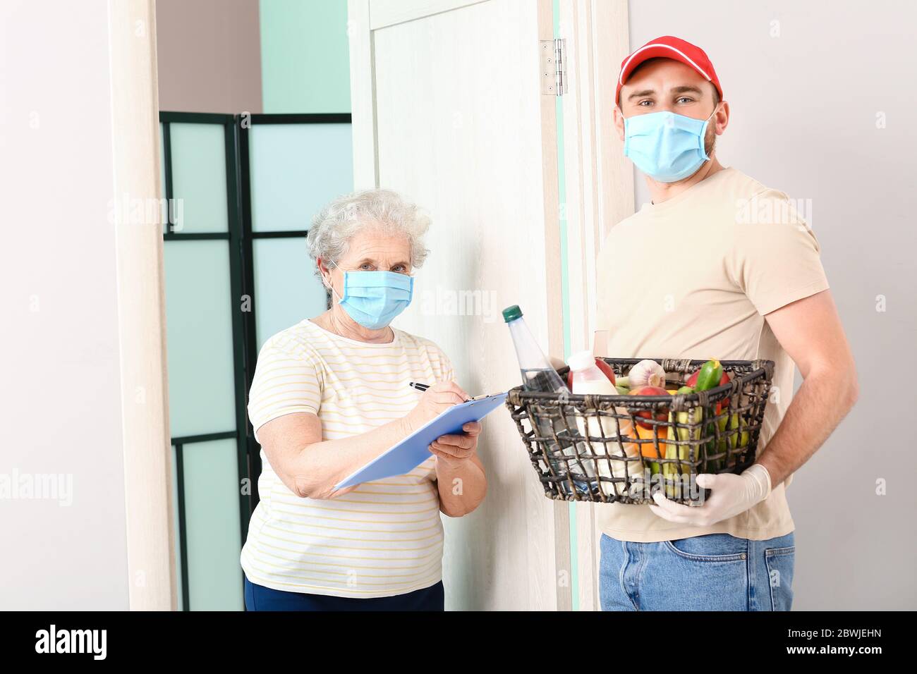 Senior woman receiving food from courier at home. Concept of epidemic ...