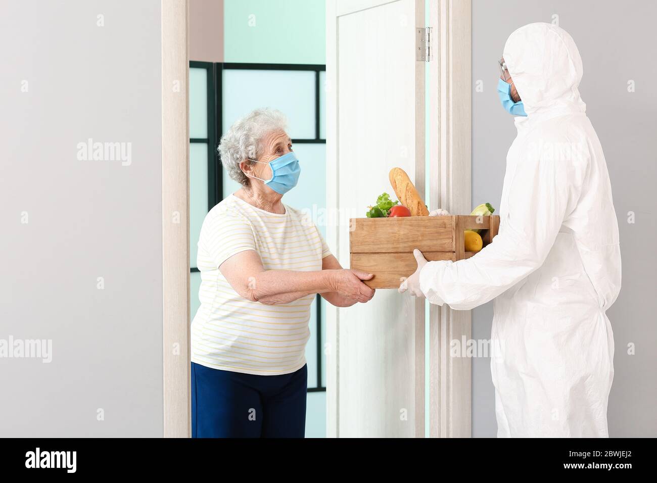 Senior woman receiving food from courier at home. Concept of epidemic ...