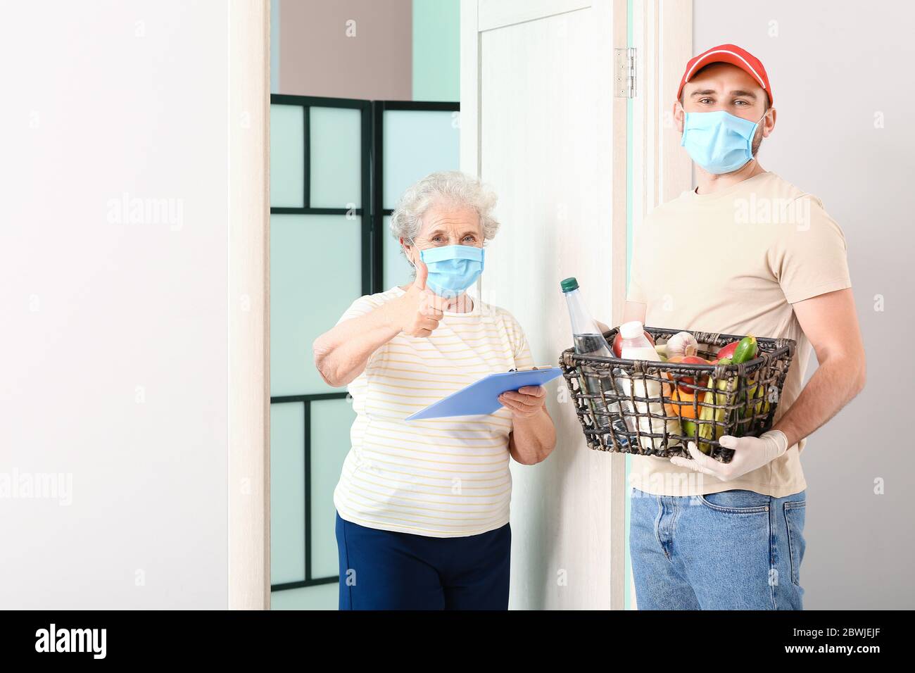 Senior woman receiving food from courier at home. Concept of epidemic ...